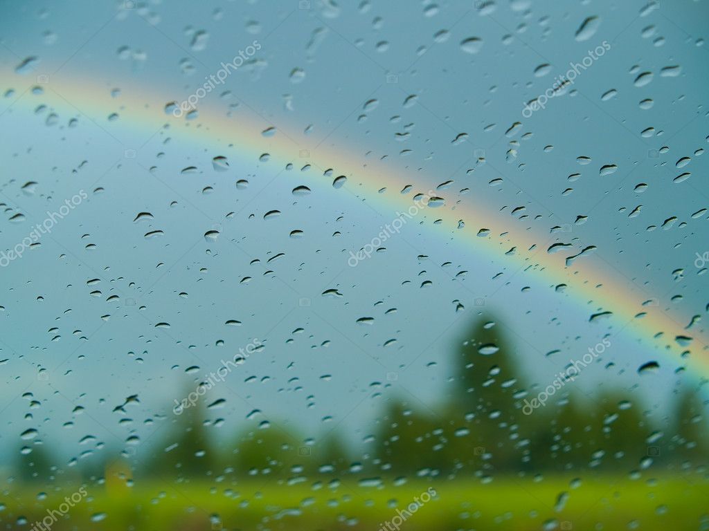 A rainbow is capture through a rain spotted windshield with the focus ...